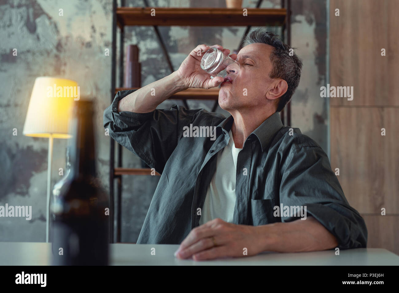 Alcohol addicted man finishing his glass of whisky Stock Photo - Alamy
