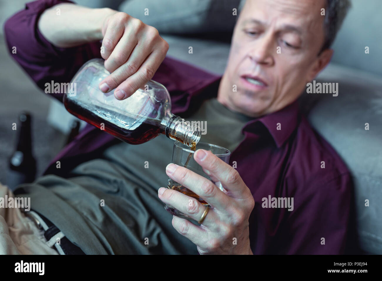Angry sad man pouring cognac in glass Stock Photo - Alamy