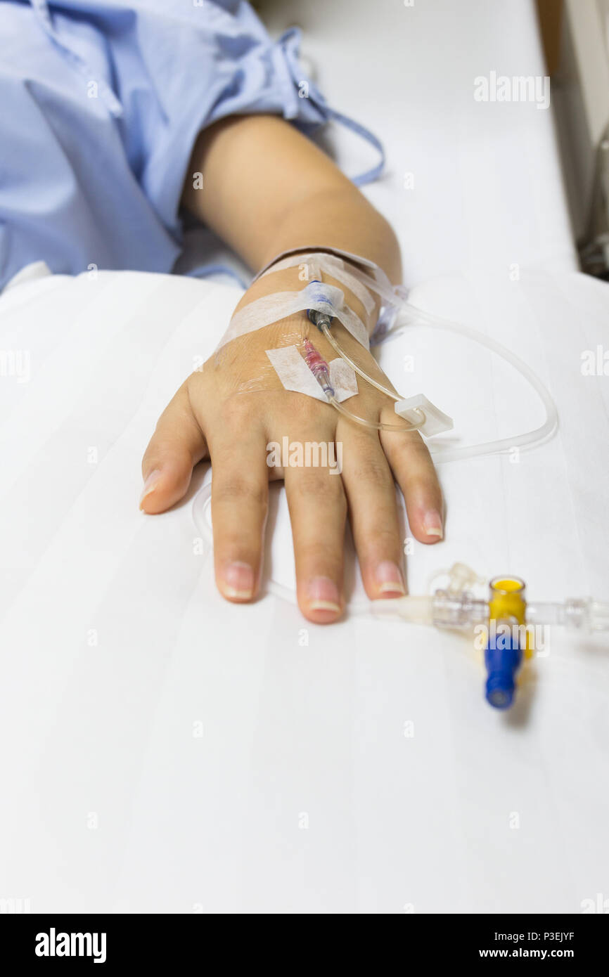 Asian woman patient is on drip receiving a saline solution on bed VIP ...