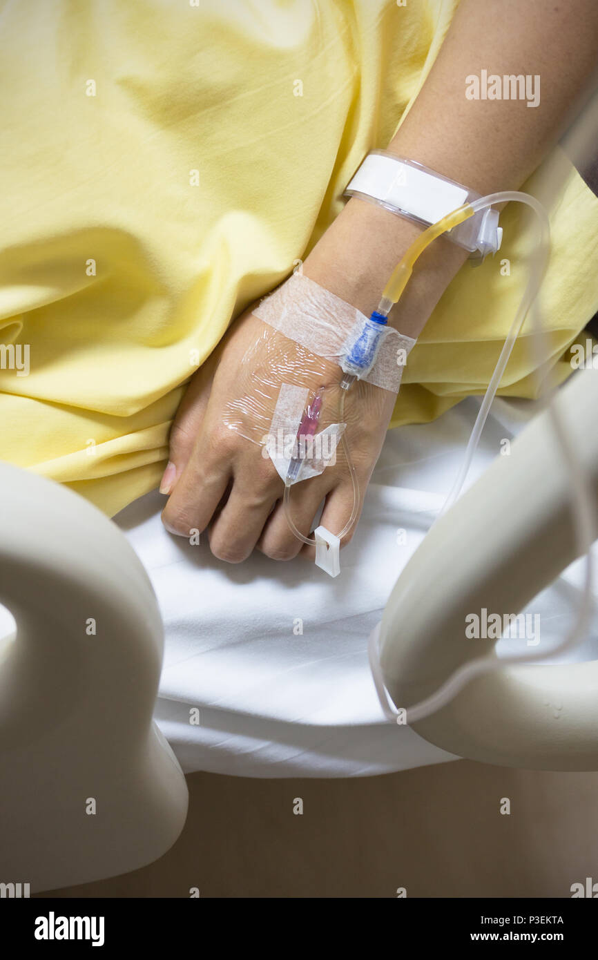 Asian woman patient is on drip receiving a saline solution on bed VIP ...