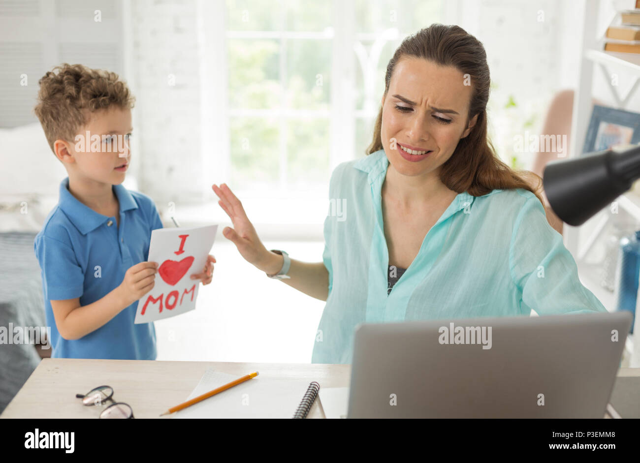 Remote worker feeling very busy while little son coming to her Stock ...