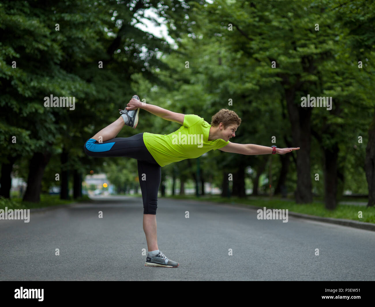 healthy female runner warming up and stretching in city park before ...