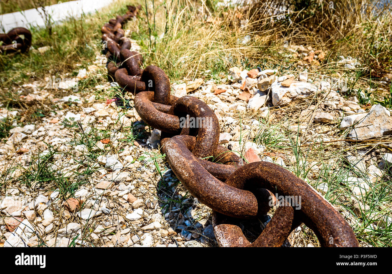 Old rusty ship anchor metal chain laying on the ground. Giant heavy ...