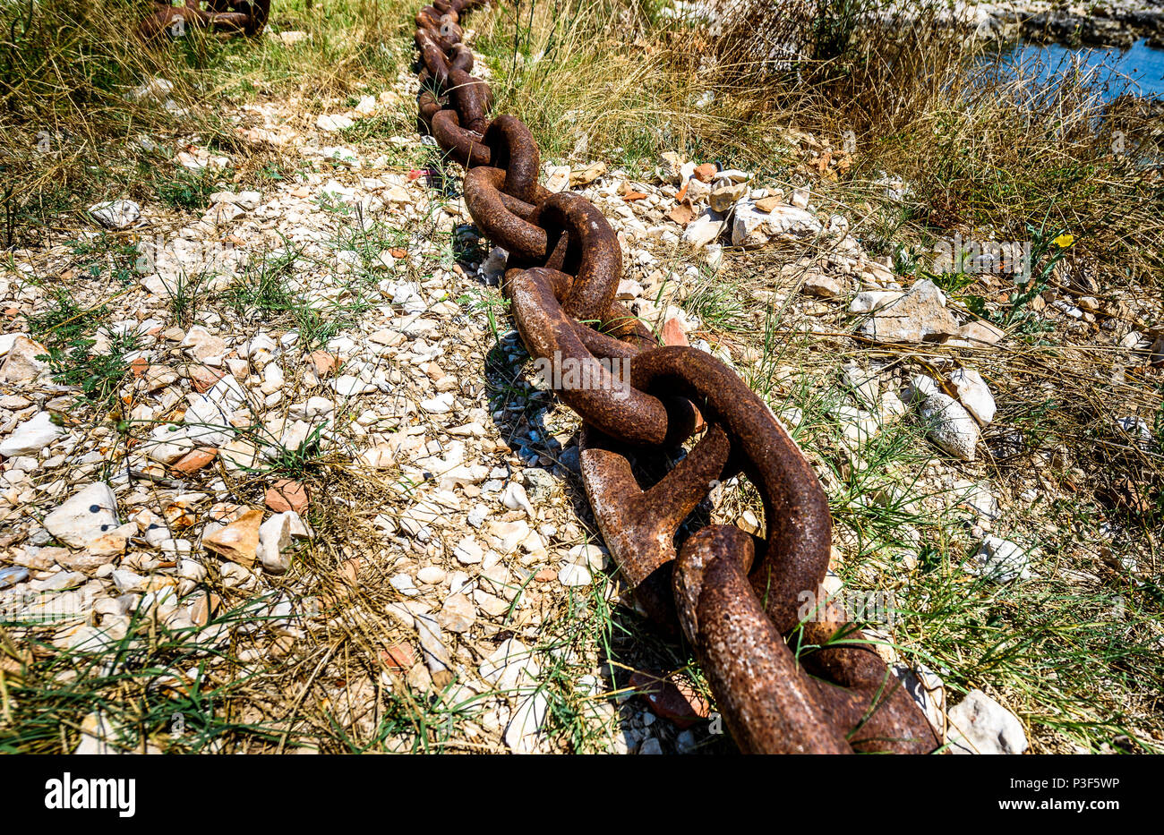 Old rusty ship anchor metal chain laying on the ground. Giant heavy ...