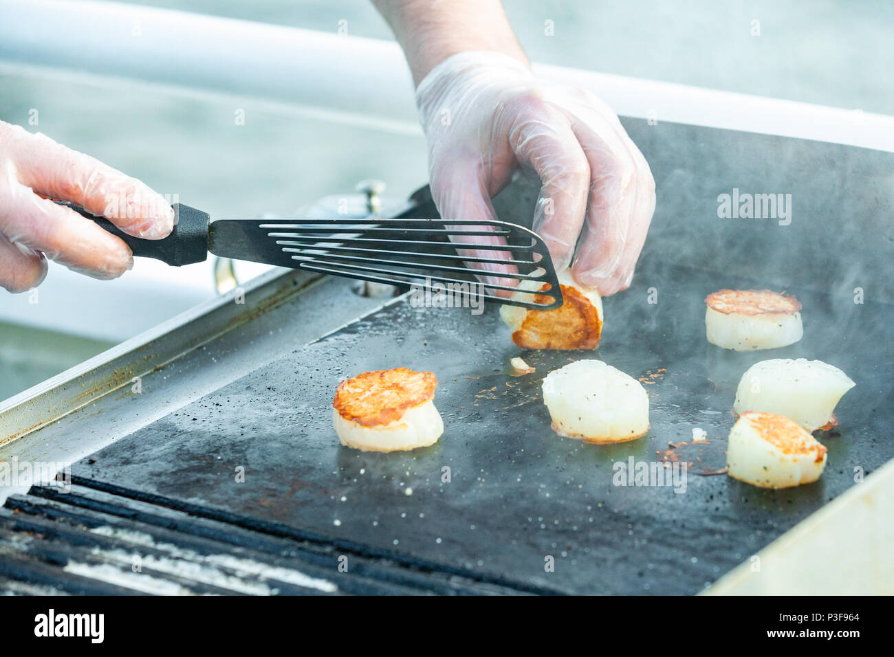 professional chef cooking fish on a barbeque. Portionally fried pieces ...
