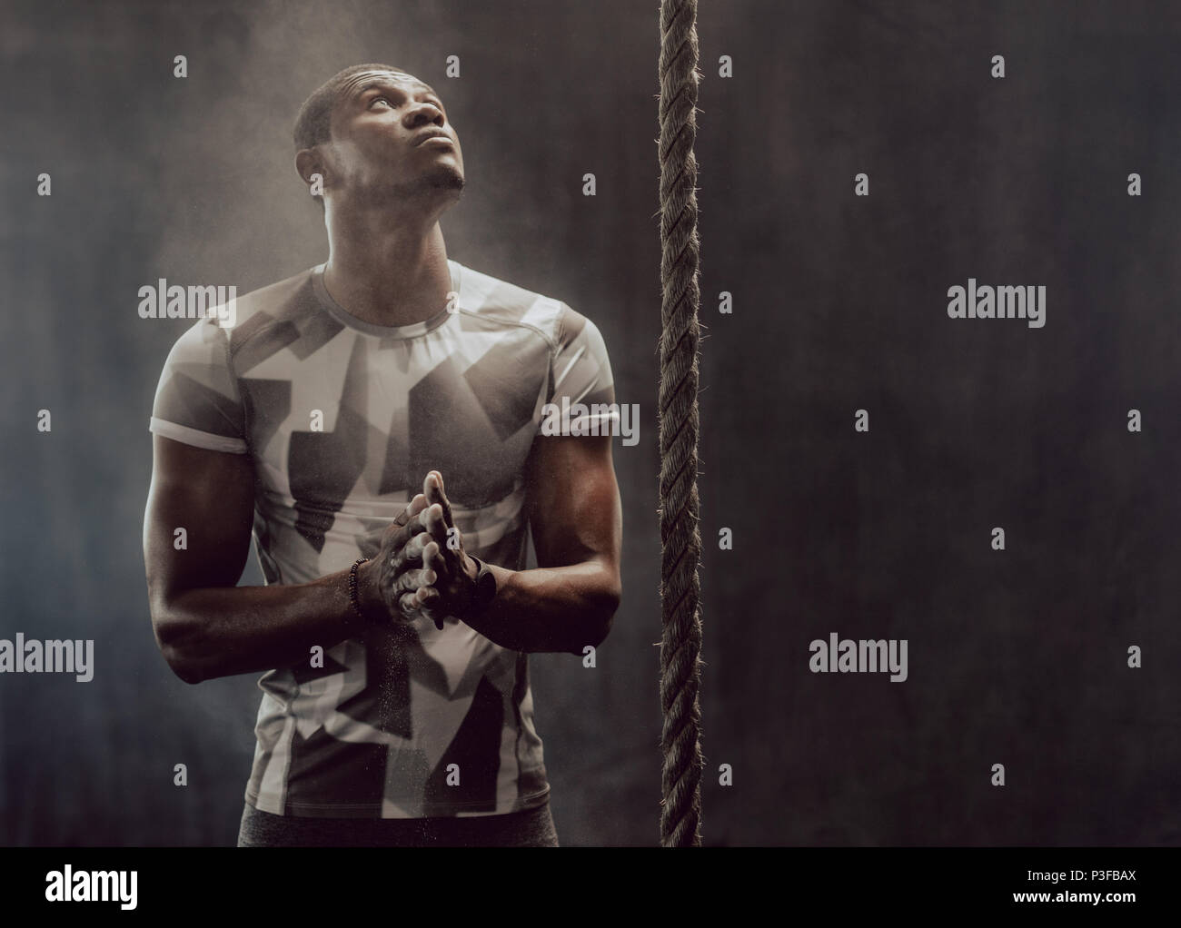 Crossfit guy chalking his hands before climbing a rope at the gym. Man ...