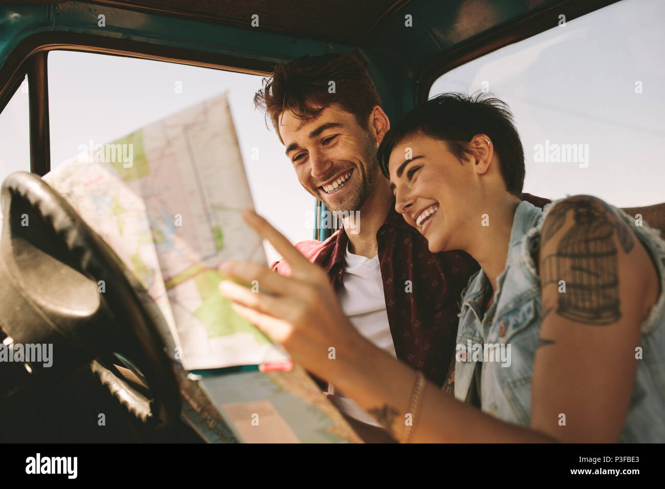 Close up of cheerful couple looking at a map sitting in car. Smiling ...