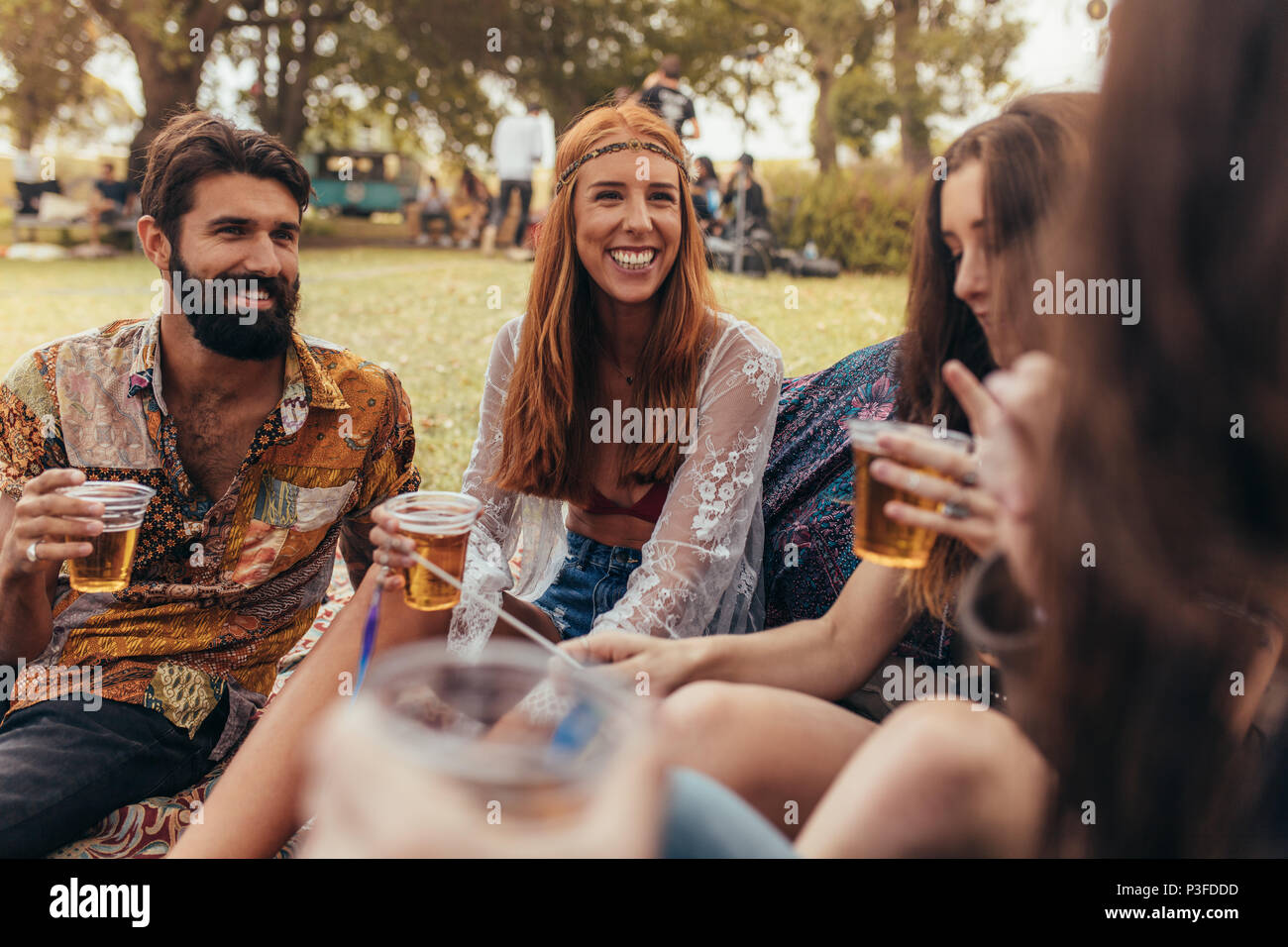 Young hippie friends partying at park with beers. Group of friends ...