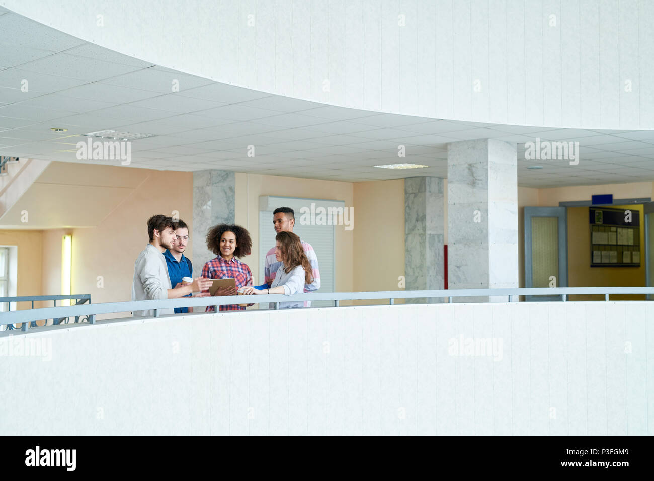 Positive groupmates discussing subjects in hall Stock Photo - Alamy