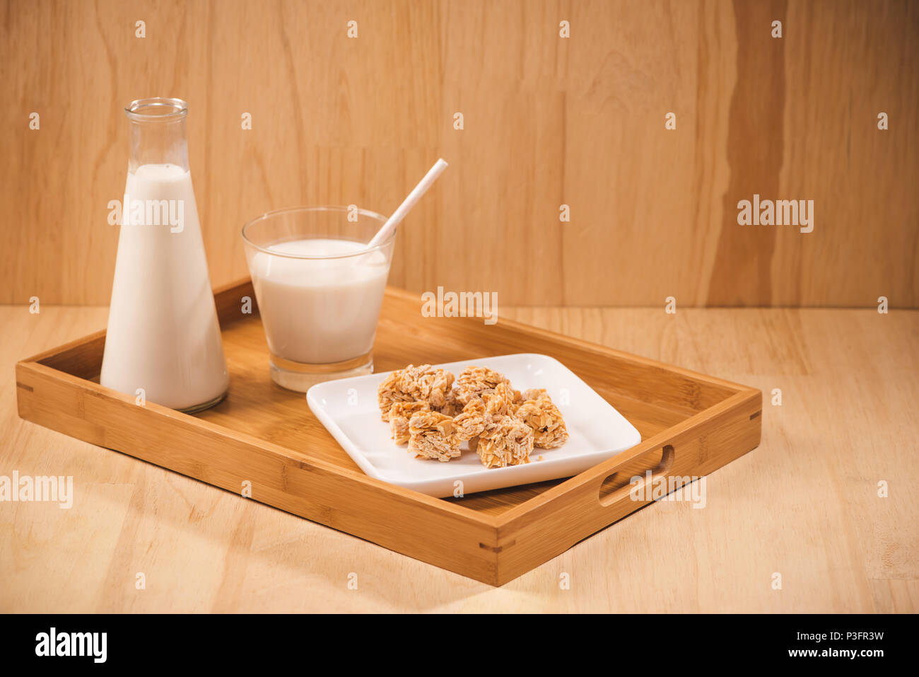Bottle with milk and glass of milk at wooden table with almond candies ...