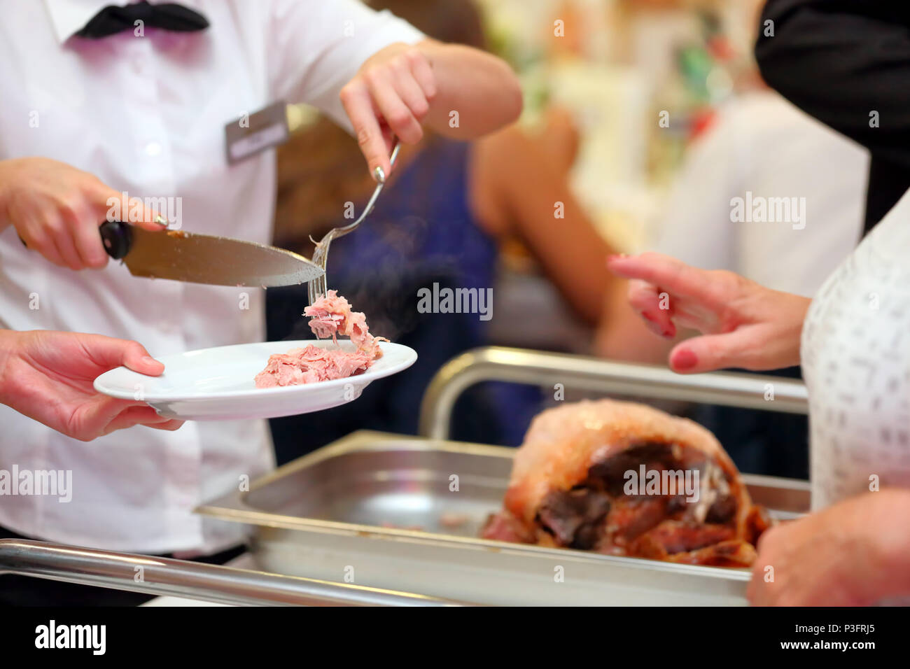 waiter sliced and serves roasted meat at the party or wedding reception ...