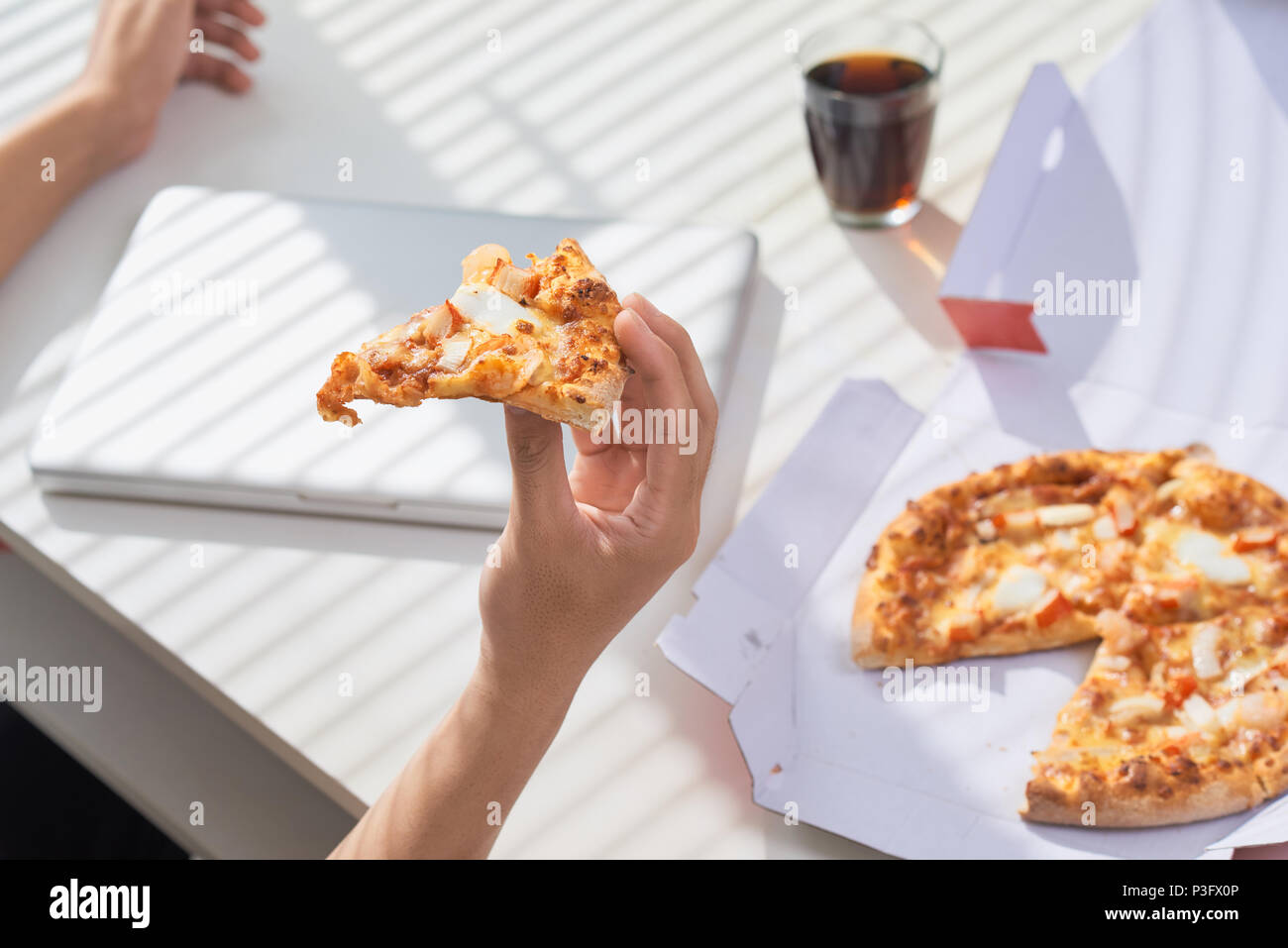 Eating pizza and social networking with a laptop Stock Photo - Alamy