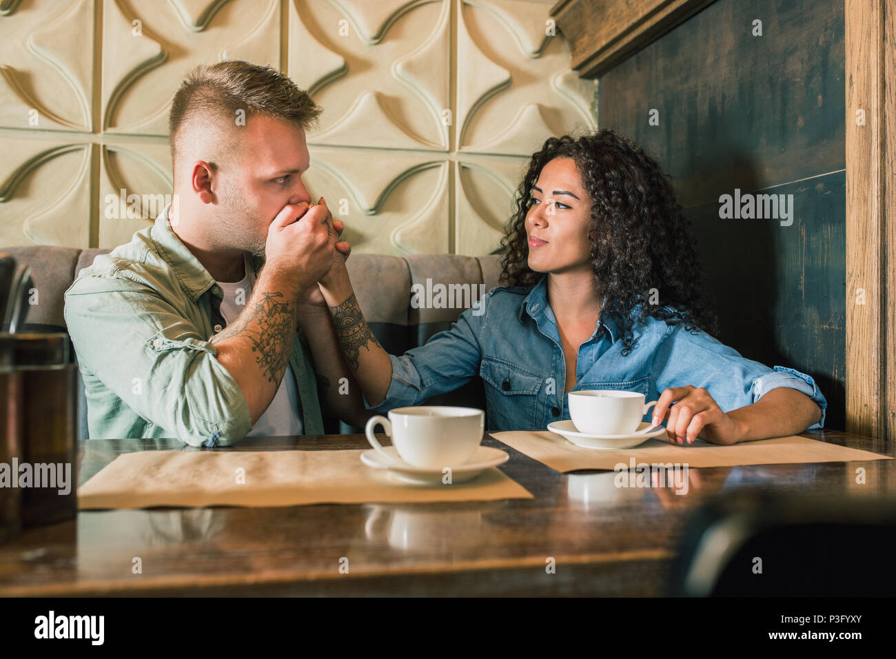 Happy young couple is drinking coffee and smiling while sitting at the ...