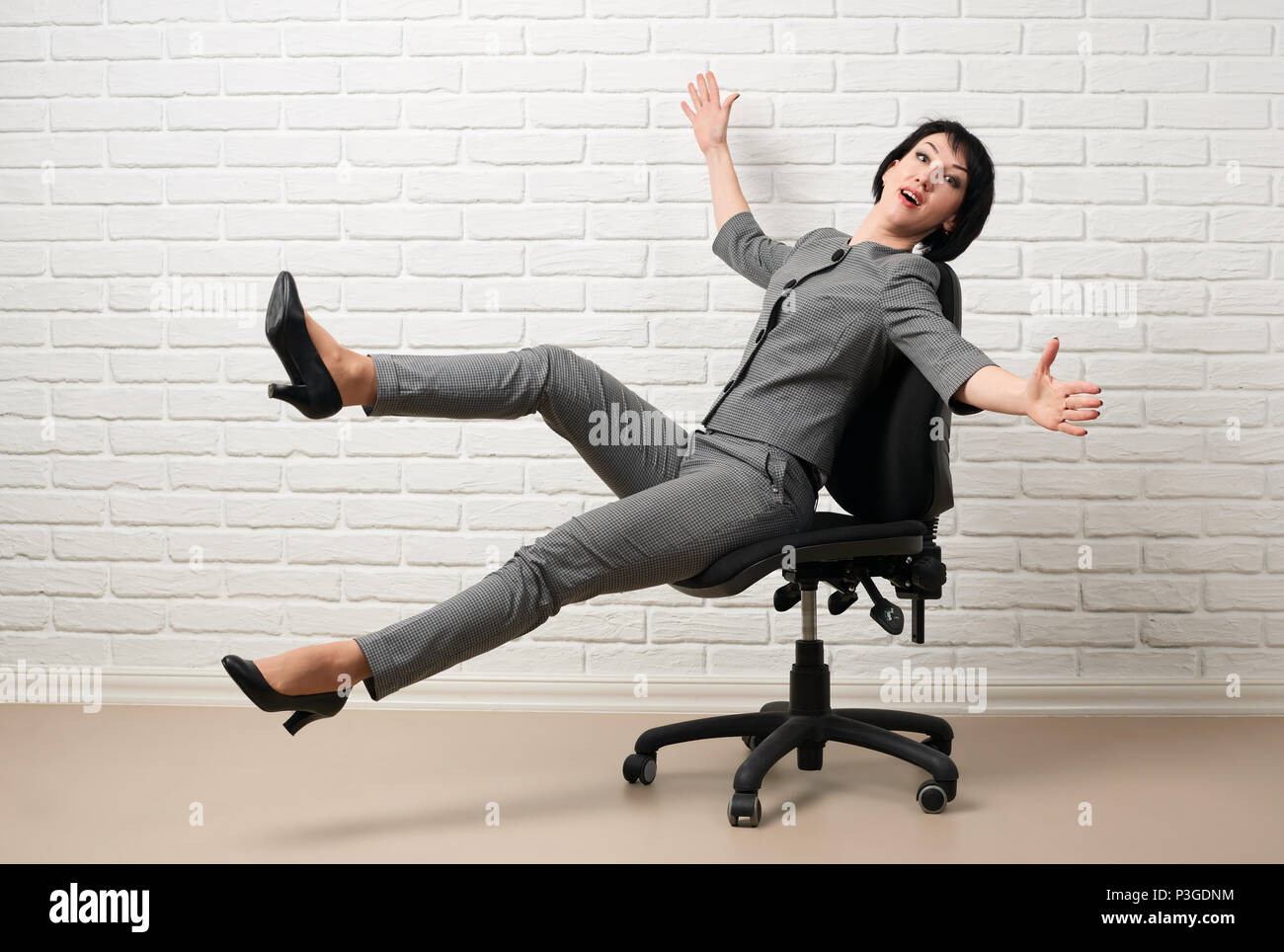 the business woman having fun, falls from chair, dressed in a gray suit ...