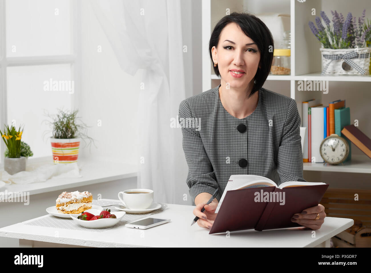 the business woman reading the diary, dressed in a gray suit poses in ...
