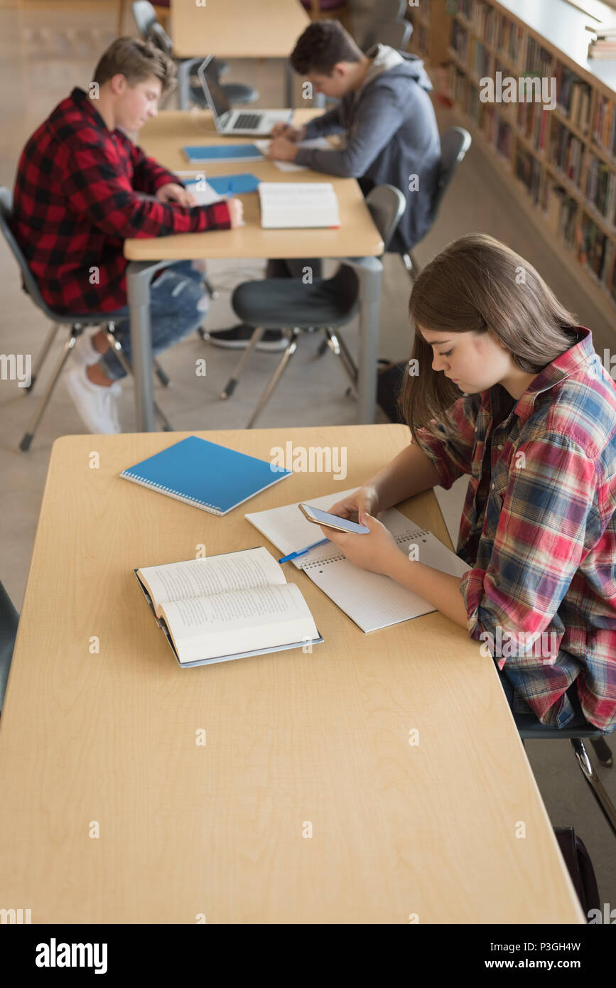 Teenage girl using mobile phone while studying Stock Photo - Alamy
