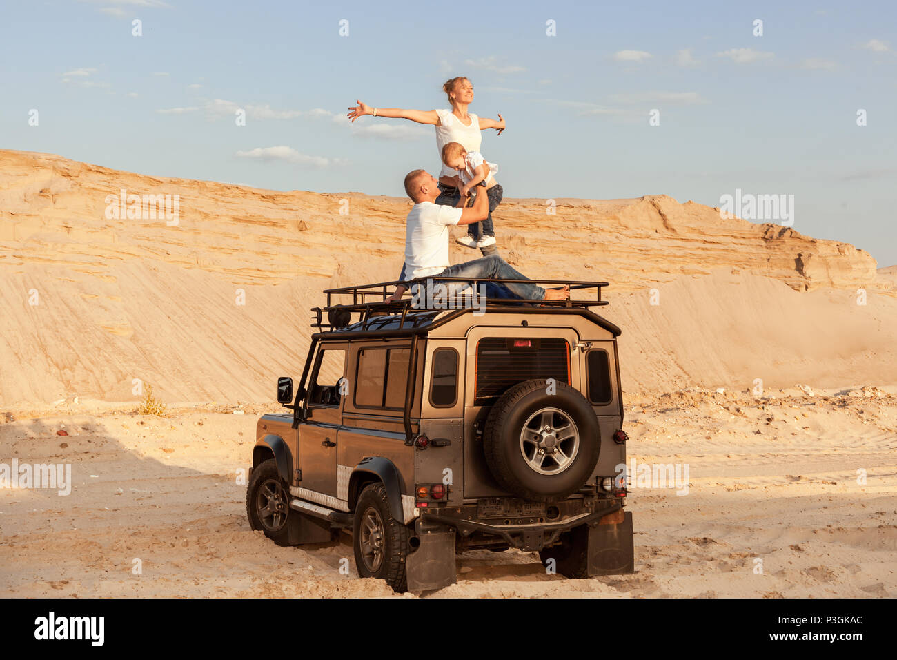 Young family with child on the roof of a car in the desert Stock Photo ...