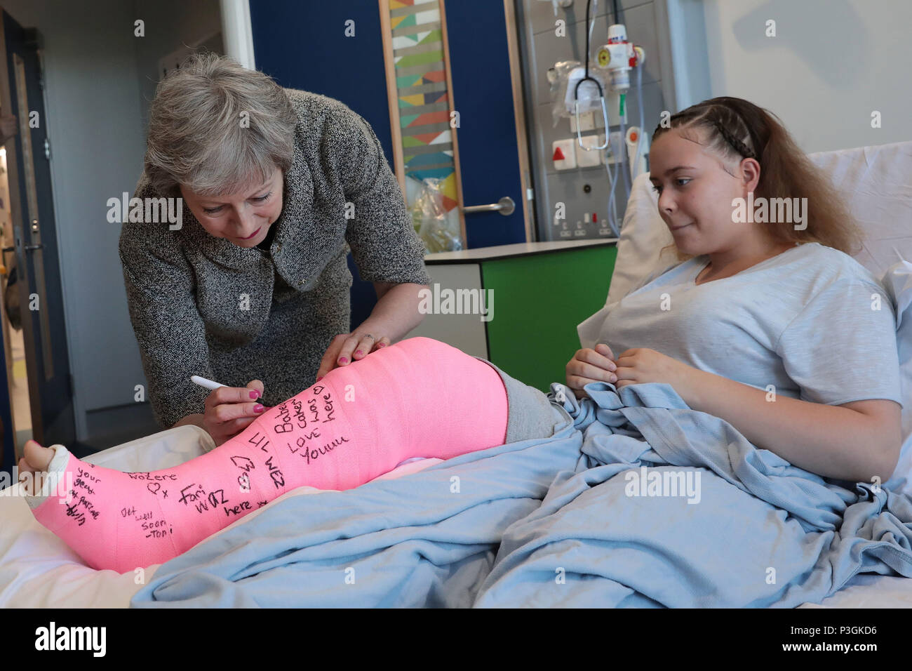 Prime Minister Theresa May signs the leg cast of patient Jade Myers, 15 ...