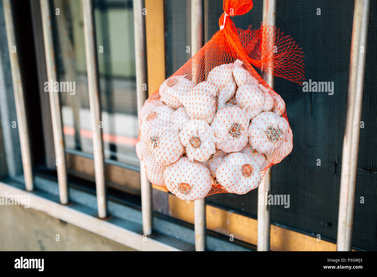 Bunch of garlic hanging in front of window Stock Photo - Alamy