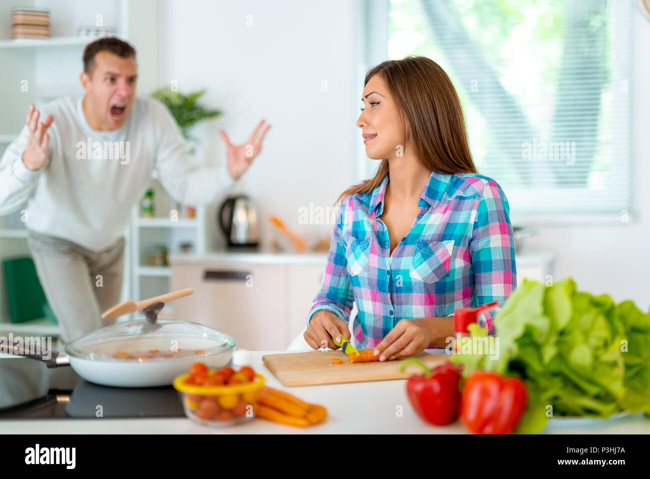 Young couple arguing in the domestic kitchen. Upset woman sitting and ...