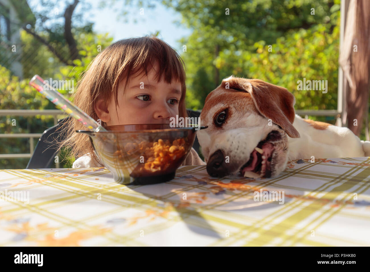 Cute little girl eat flakes with milk . Summer sunny day in the garden ...
