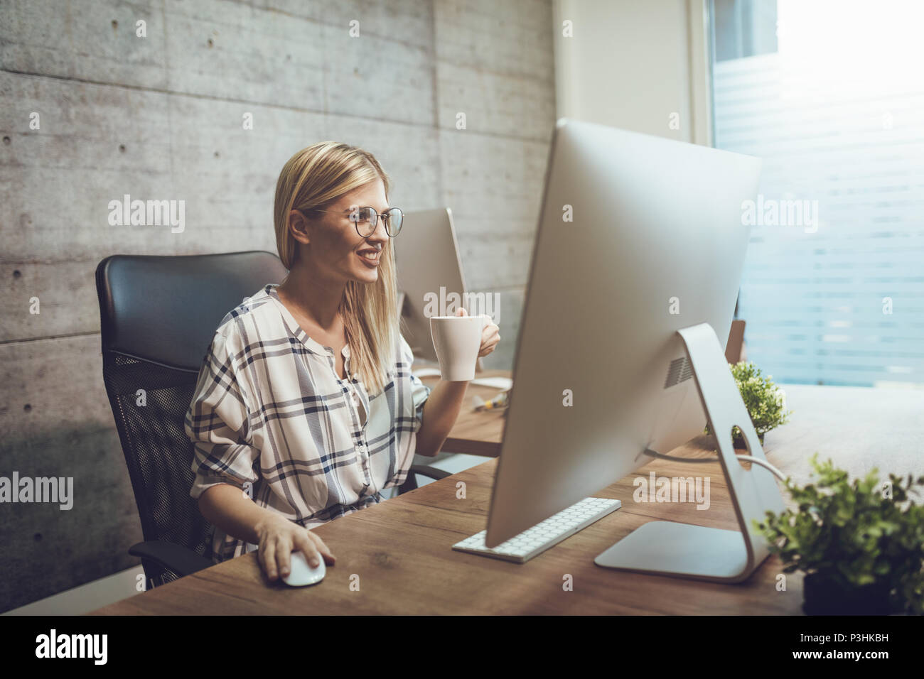 Young cute happy freelance female designer working on computer and ...