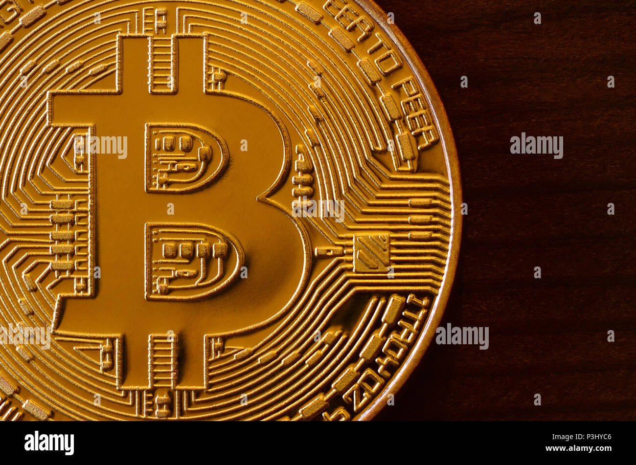 One new golden physical bitcoin is lies on dark wooden backgound, close ...