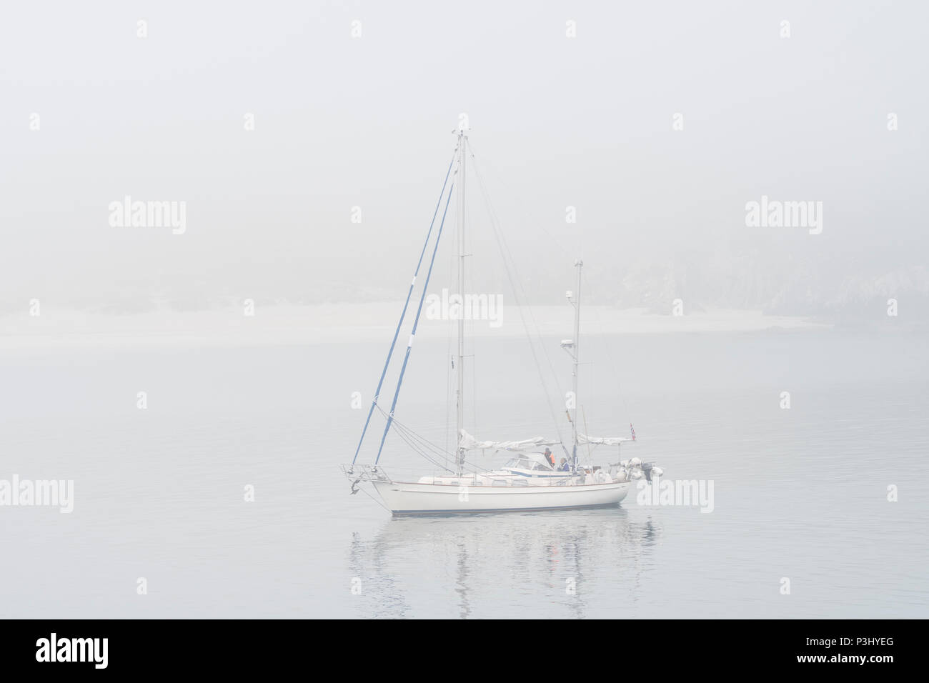 Sailboat / sailing boat / yacht with lowered sails anchored near beach ...