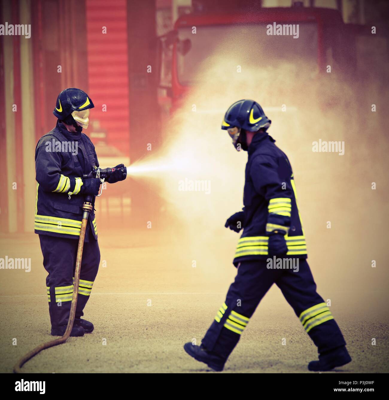 two firefighters during the extinguishing of a fire using the foamer ...