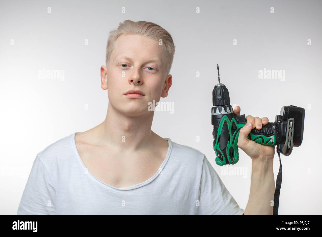 Portrait of a smiling handsome young man holding drill against white ...
