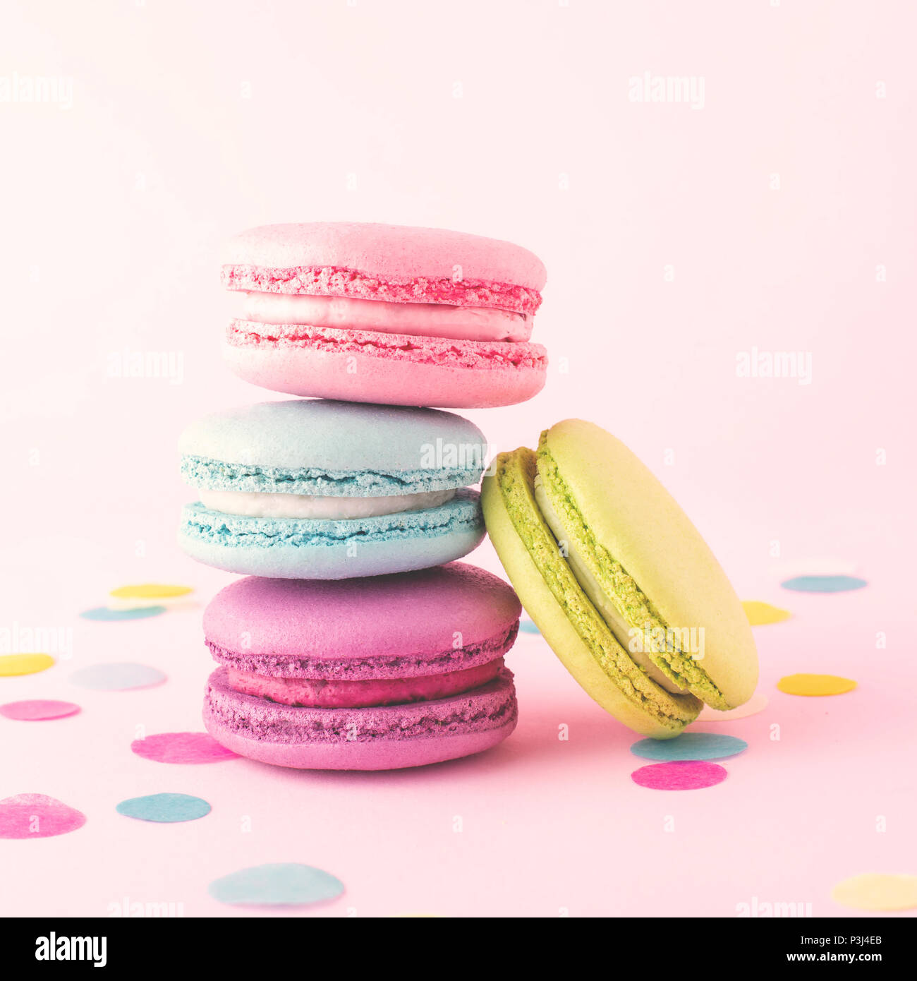 Stacking sweet colorful macarons on pink background decorated with ...