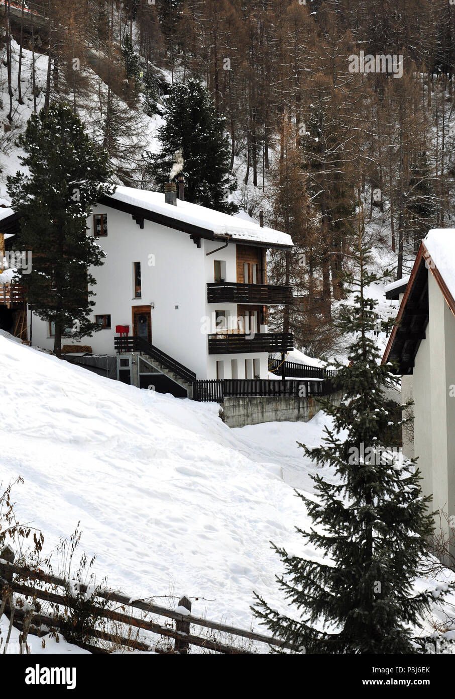 Charming snow capped cabin homes atop a mountain slope in Zermatt ...