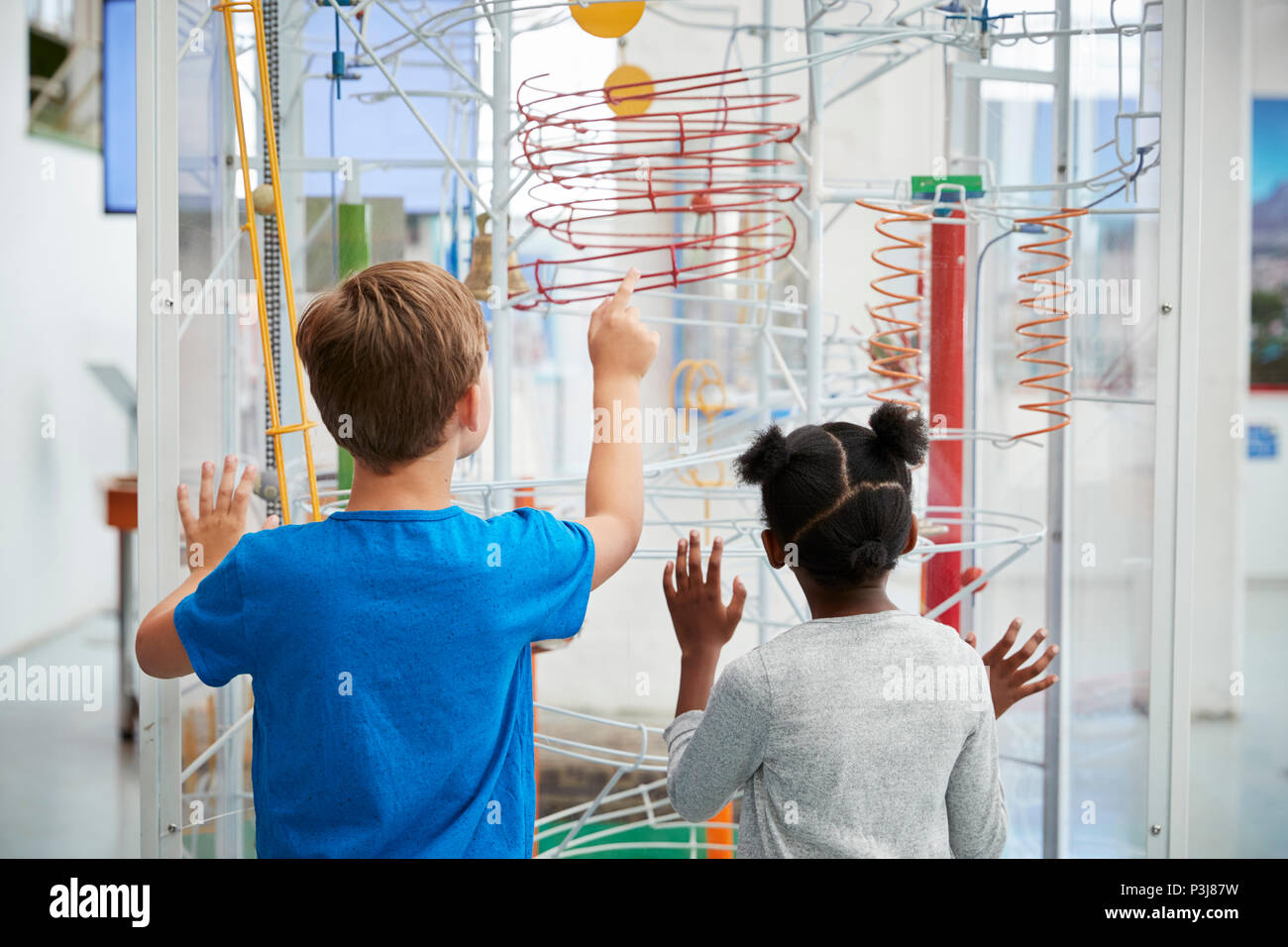 Two kids looking at a science exhibit, back view Stock Photo - Alamy