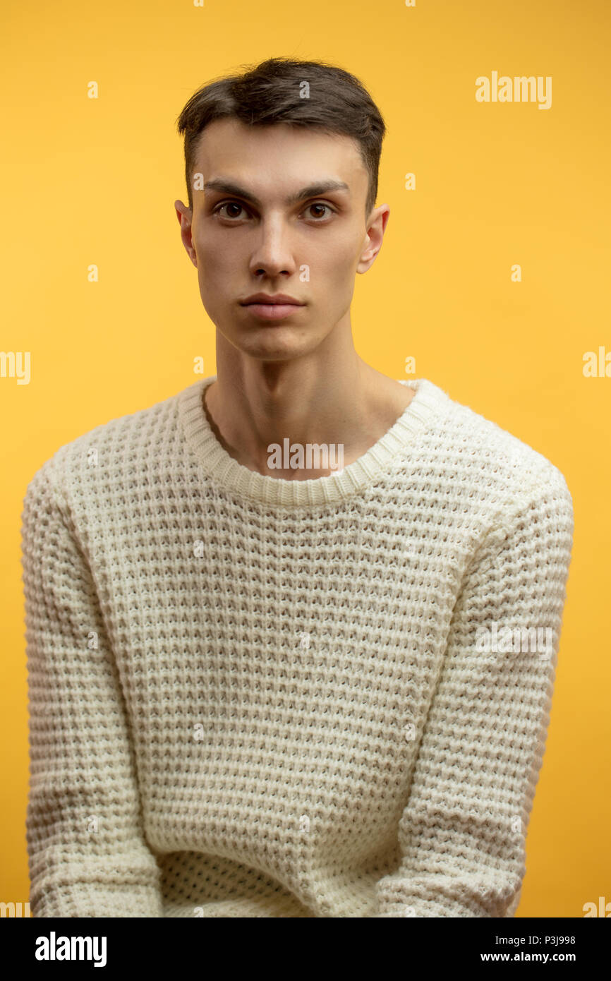 Portrait of a smart serious young man standing against yellow ...