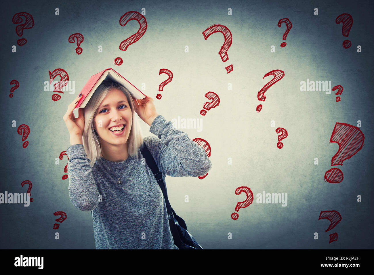 Pretty smiling student girl holding a opened book over her head and ...