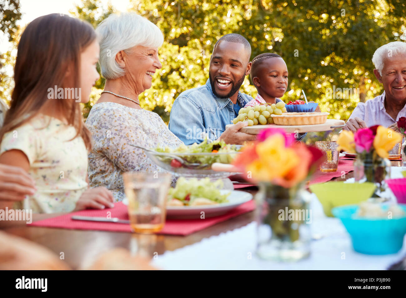 Family and friends talking over lunch at a table in garden Stock Photo ...