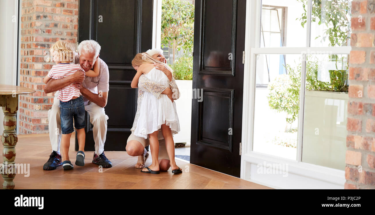 Visiting grandparents bend and kneel to hug grandchildren Stock Photo ...