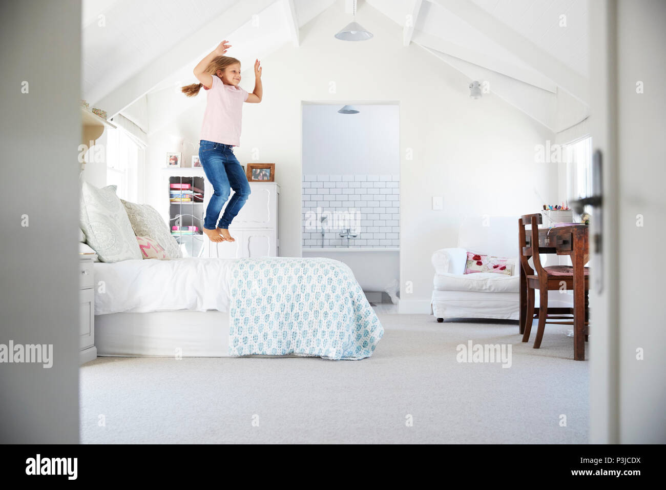 Happy young girl jumping on her bed in her bedroom Stock Photo - Alamy