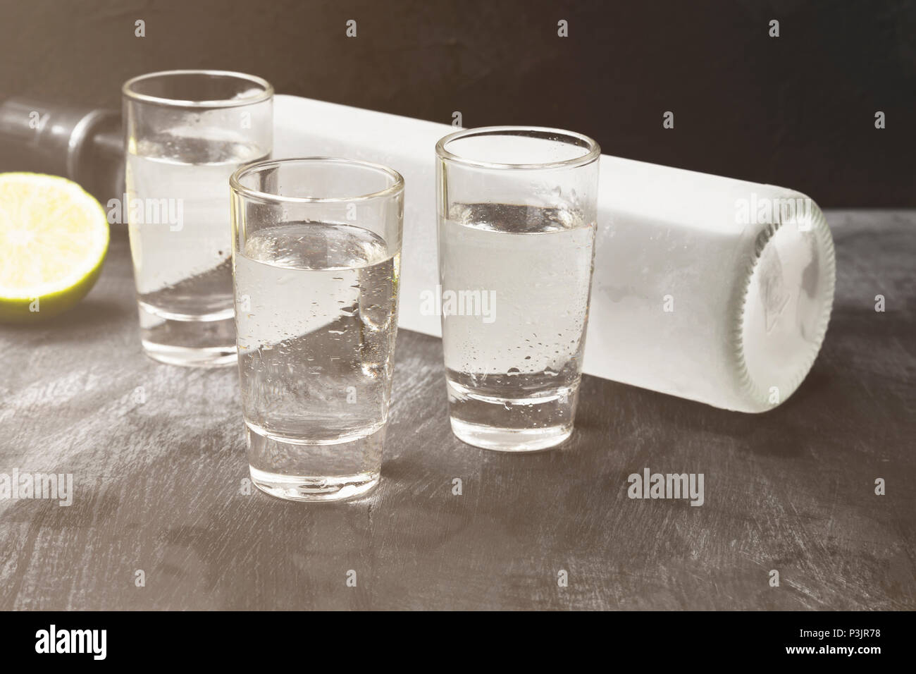 Cold vodka in shot glasses on a black background. Toned Stock Photo - Alamy