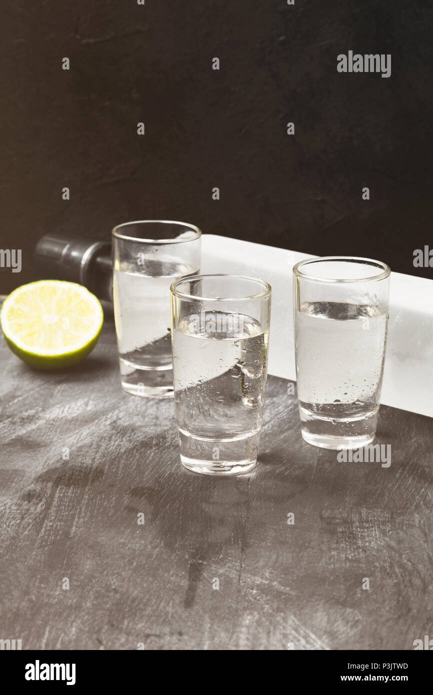 Cold vodka in shot glasses on a black background. Toned Stock Photo - Alamy