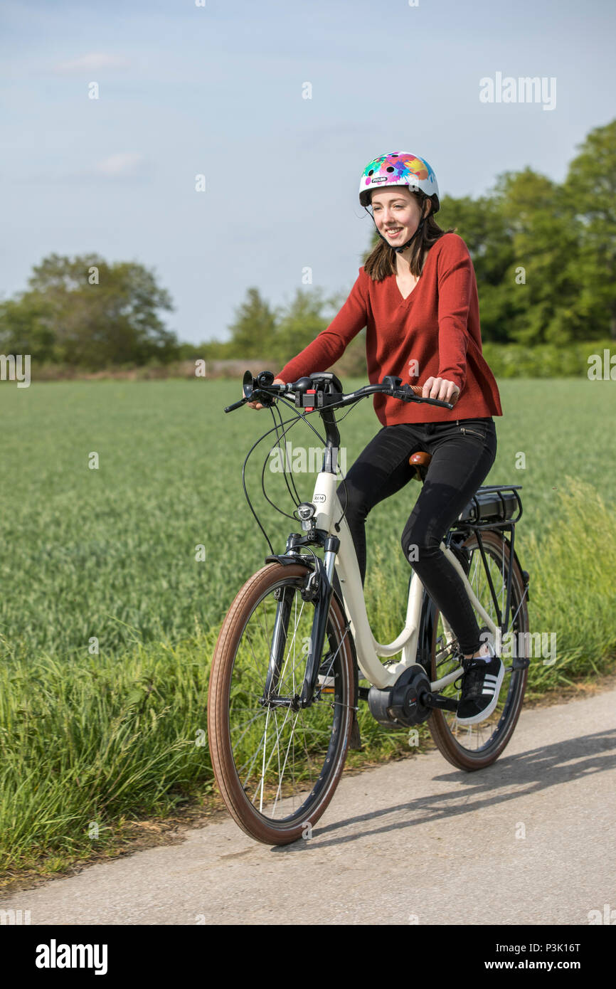 Young woman rides an e-bike, electric bike, electric motor assisted ...