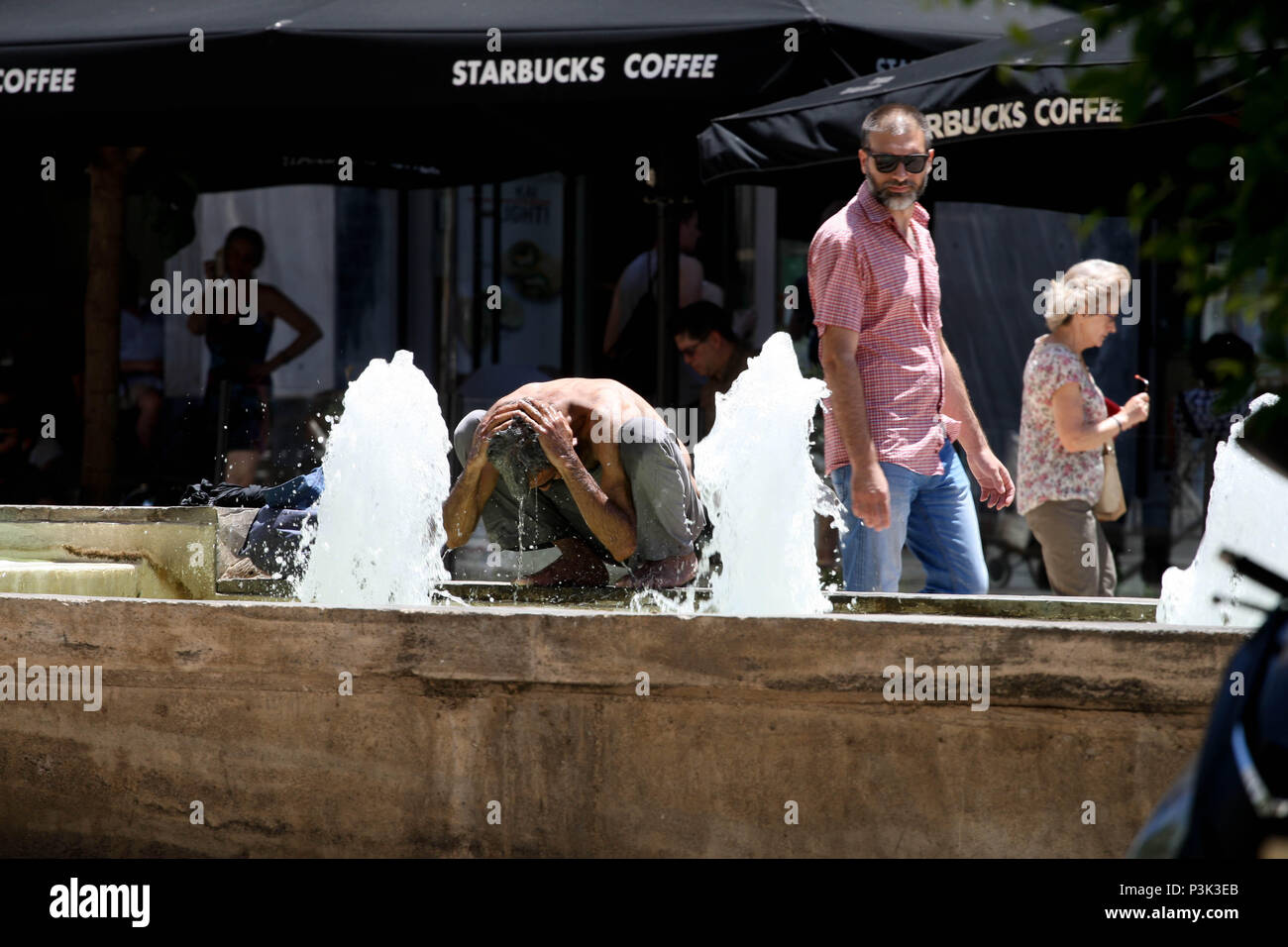 A homeless man make a shower at the fountain in the center of Athens ...