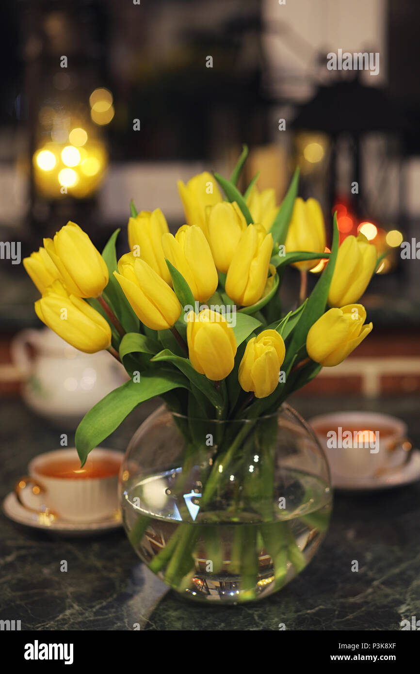 A bouquet of yellow tulips in a vase in the interior of a retro room ...