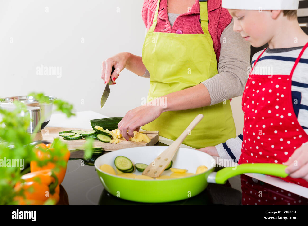 Mother cooking in the kitchen, son watching Stock Photo - Alamy