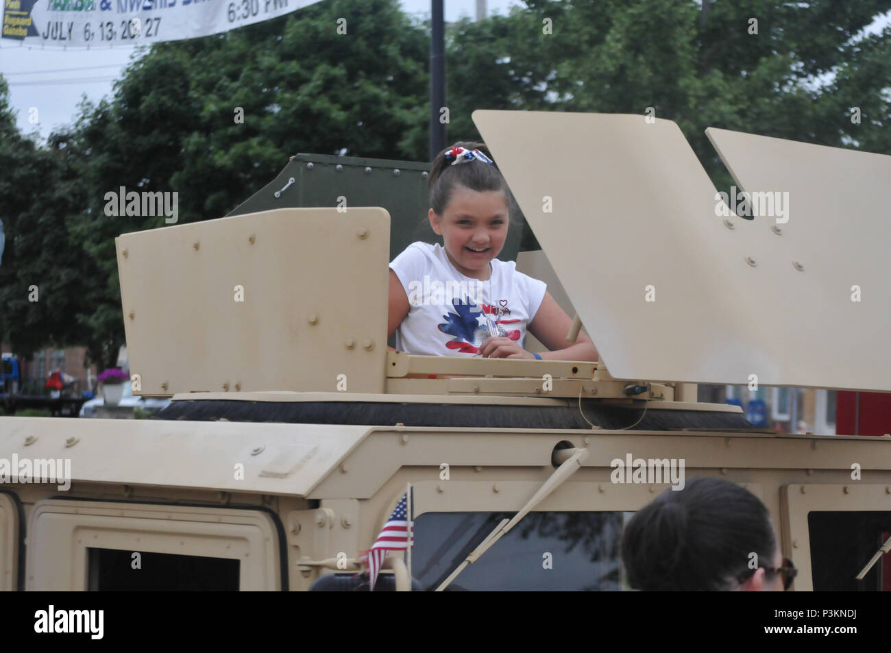 A local child poses in the gunner’s hatch of a Humvee during ...