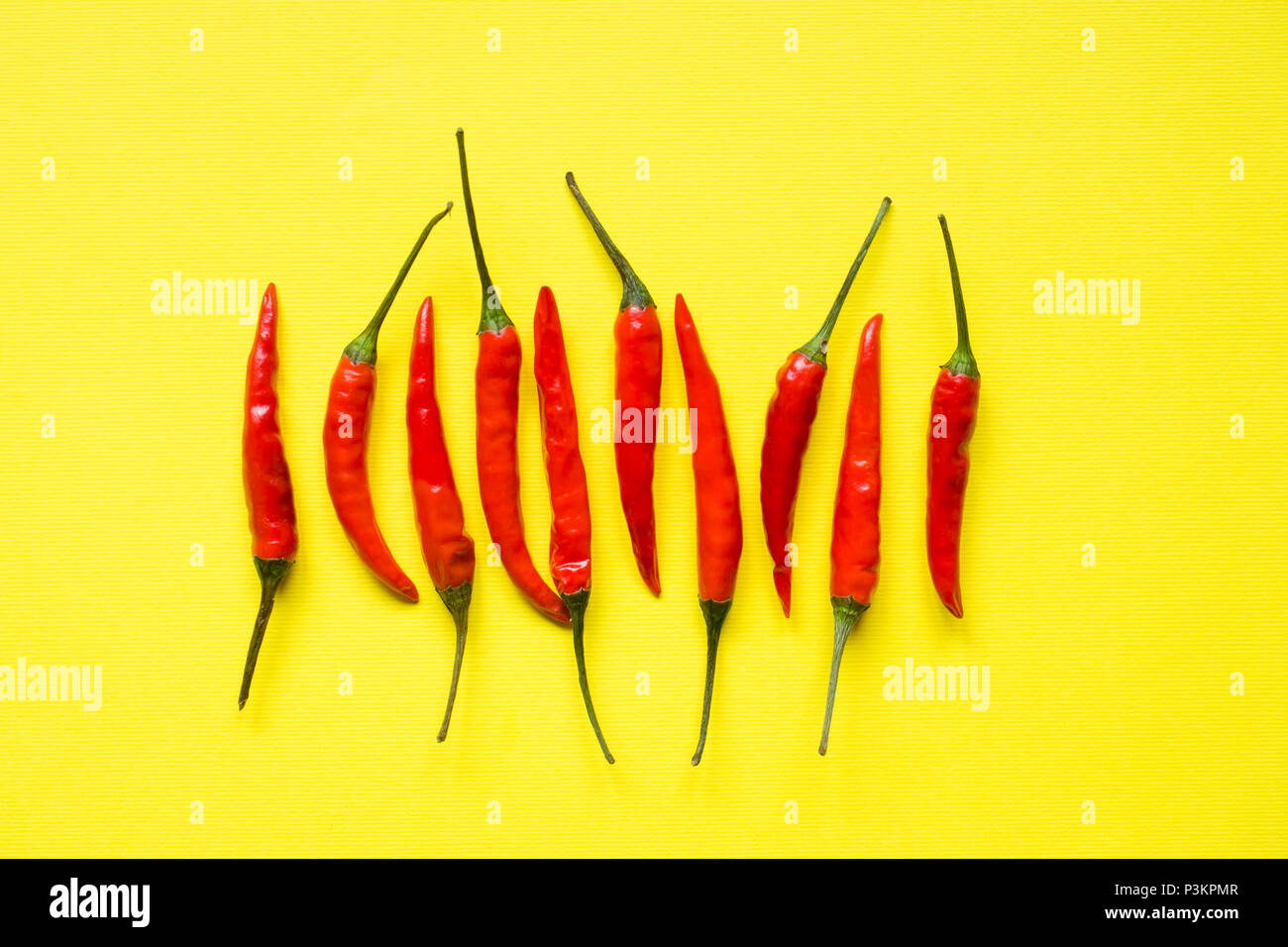 Red chili pepper pods on bright yellow background Stock Photo - Alamy