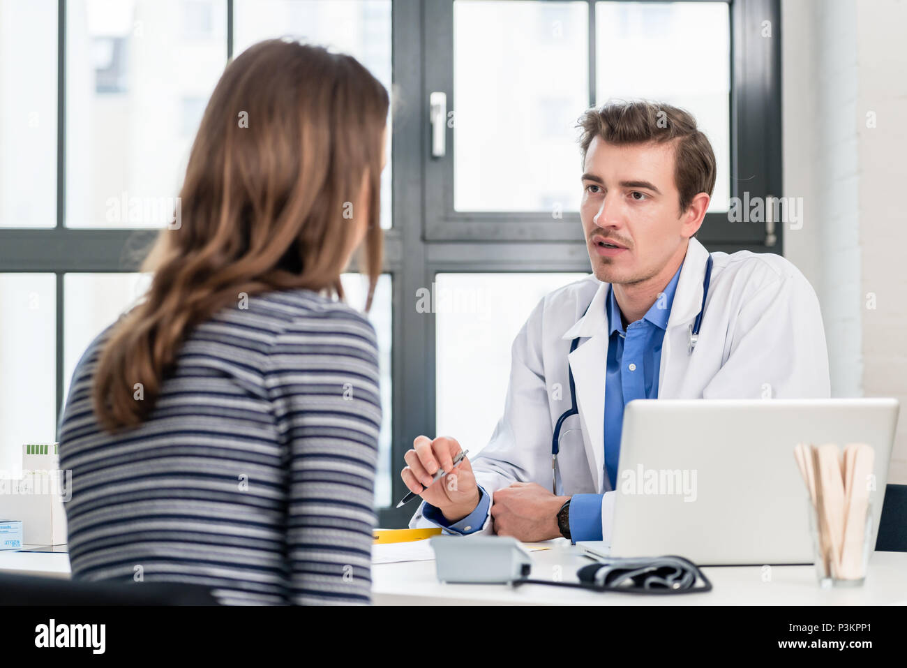 Young devoted doctor listening with attention to his patient Stock ...
