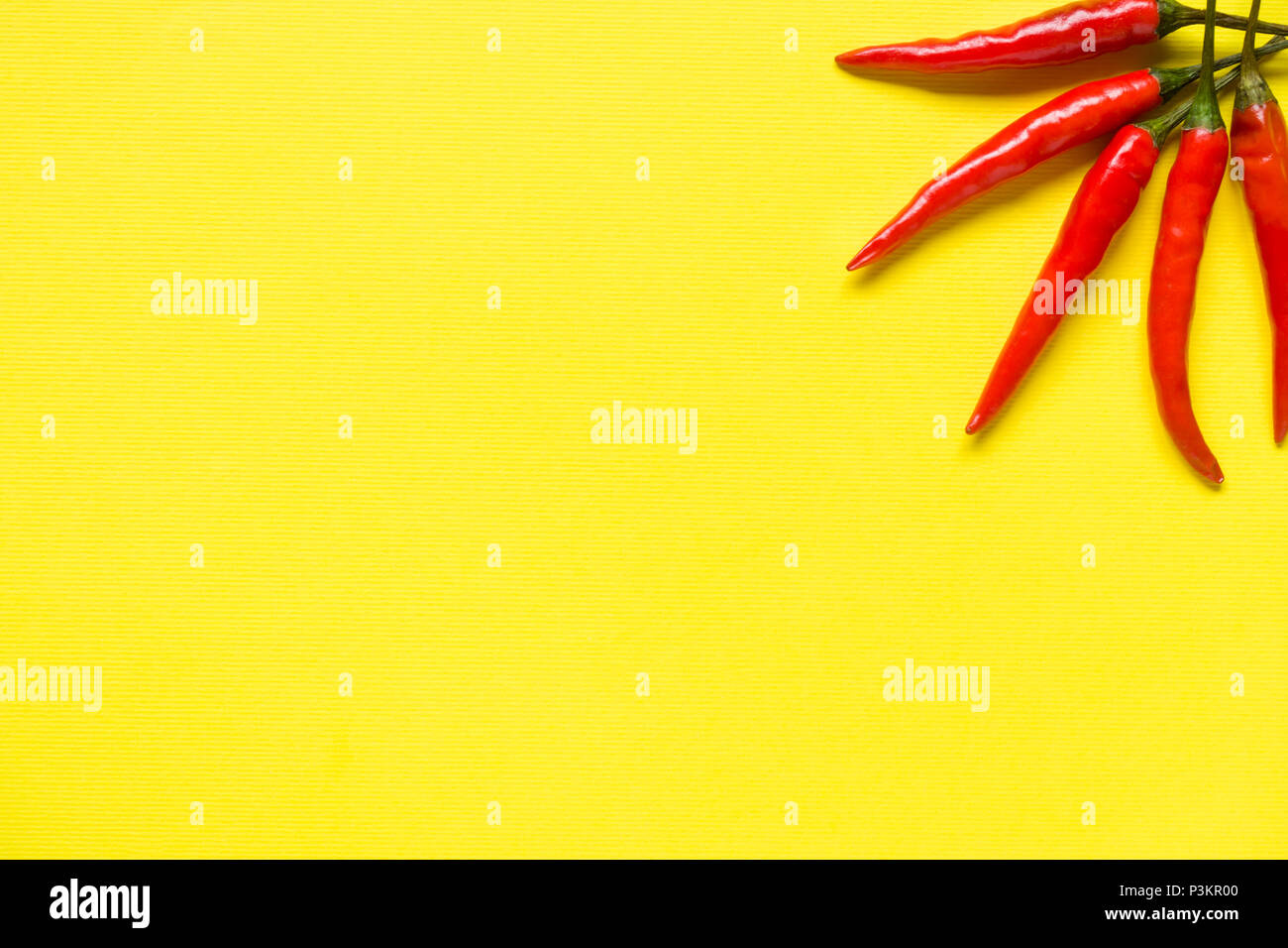 Red chili pepper pods on bright yellow background Stock Photo - Alamy