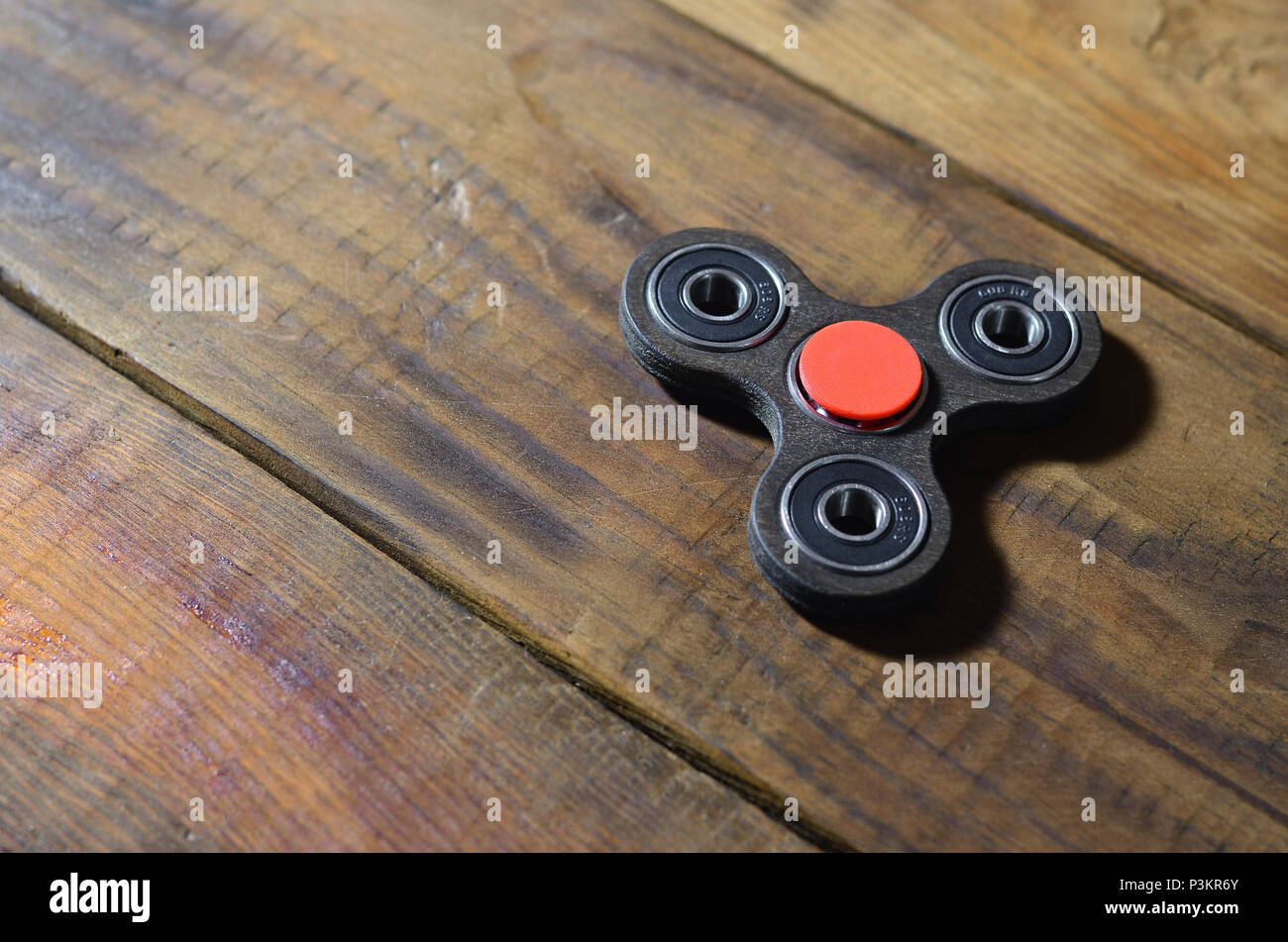 A rare handmade wooden fidget spinner lies on a brown wooden background ...