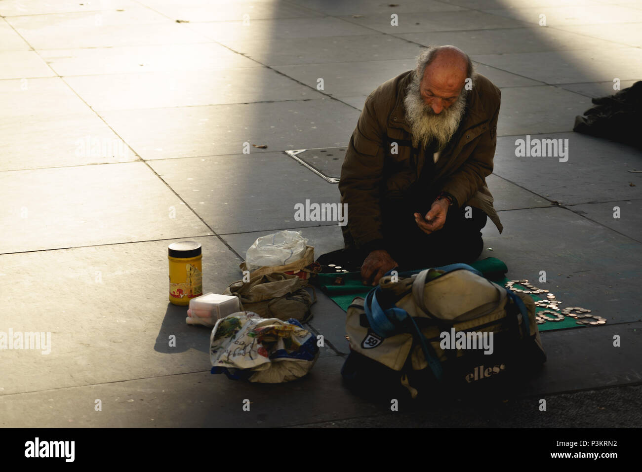 London, UK - November 2017. An old homeless beggar in Trafalgar Square ...